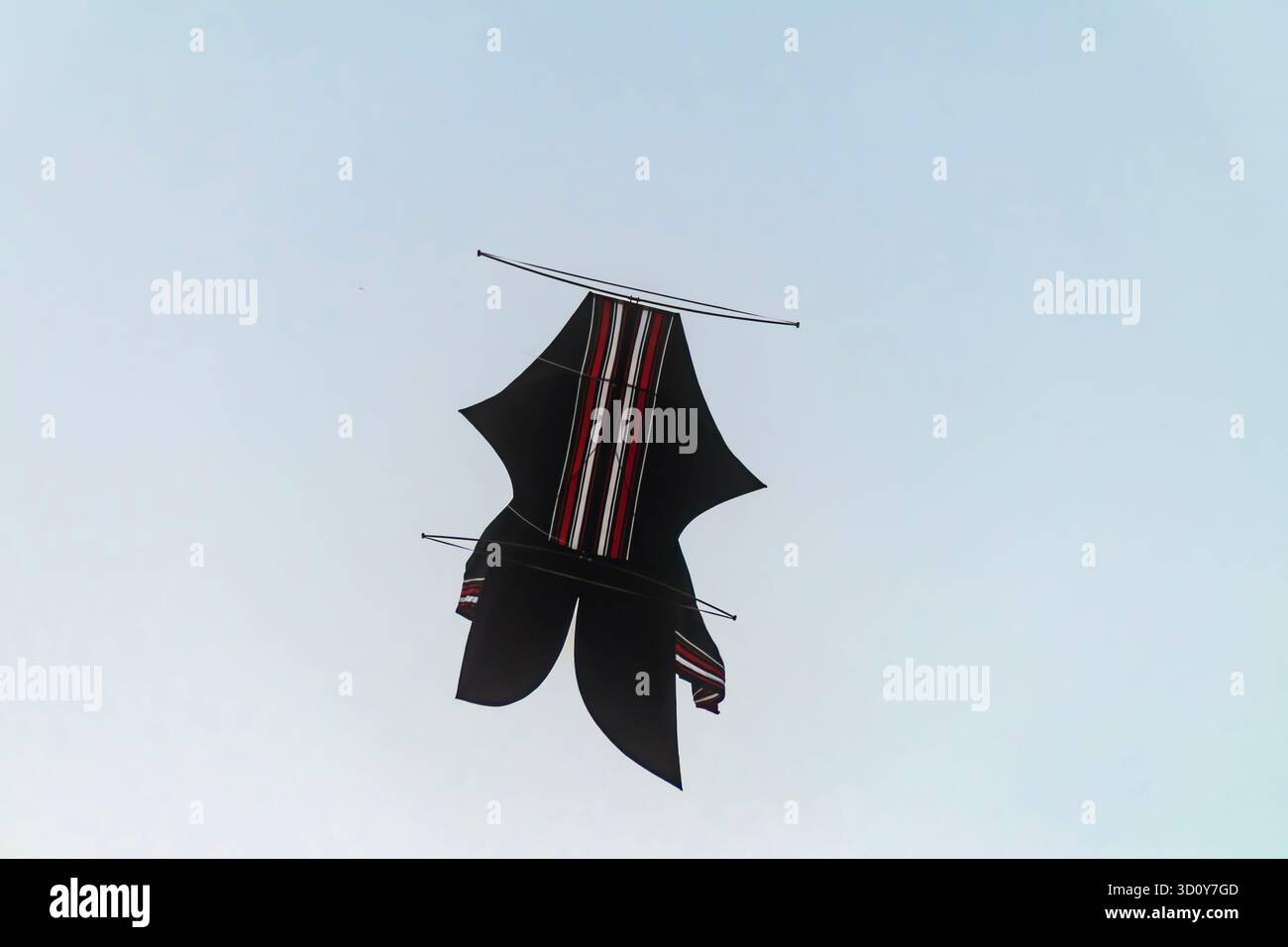 Large black Balinese traditional Bebean kite flying in the sky with ...