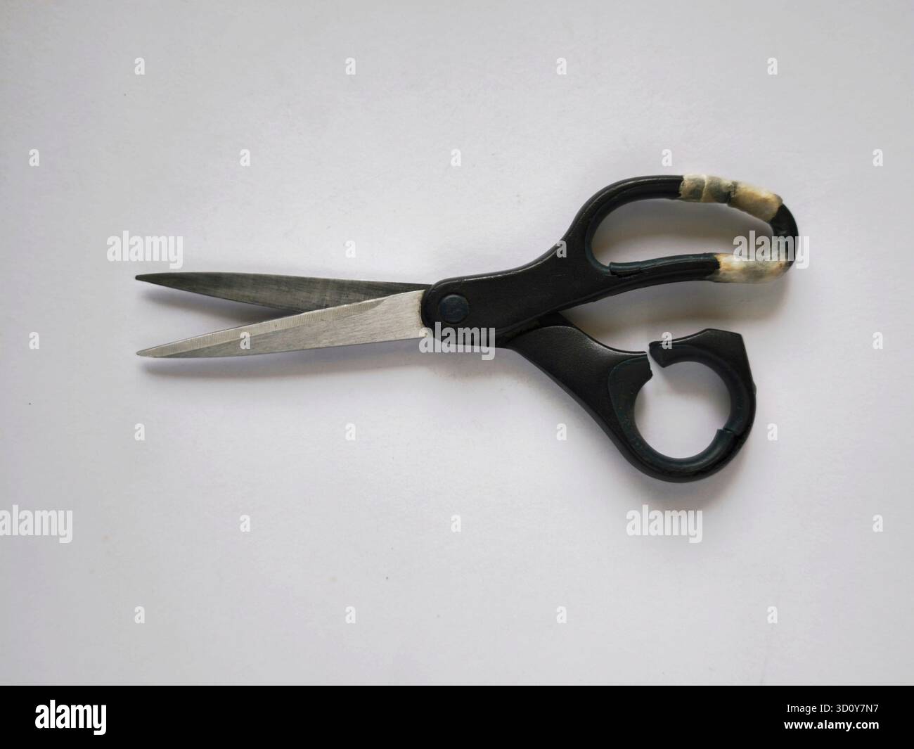 A pair of scissors with a broken black handle that looks like it has ...