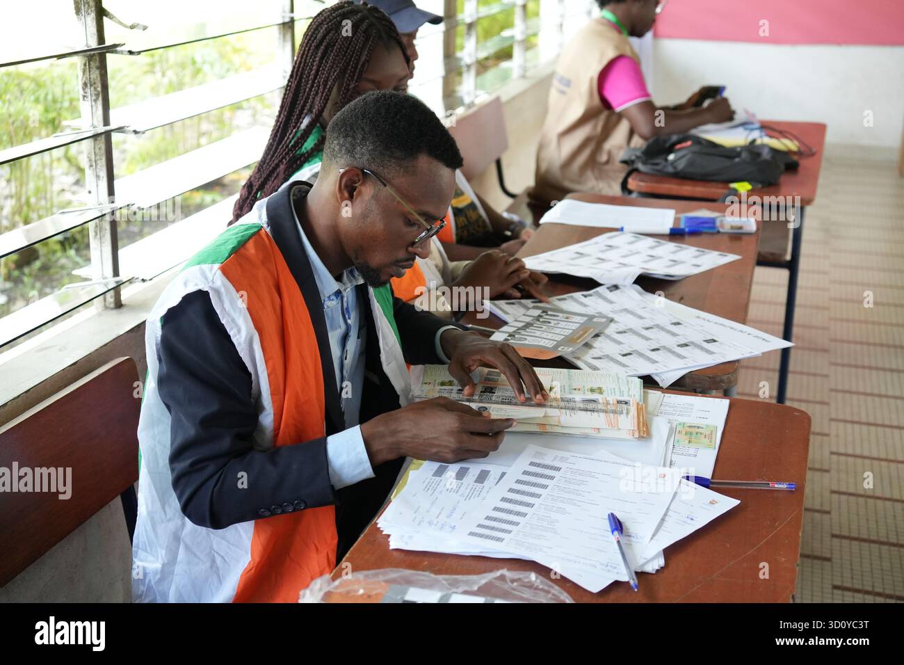 Abidjan, Cote d'Ivoire. 25th Oct, 2025. Staff members check voter ...