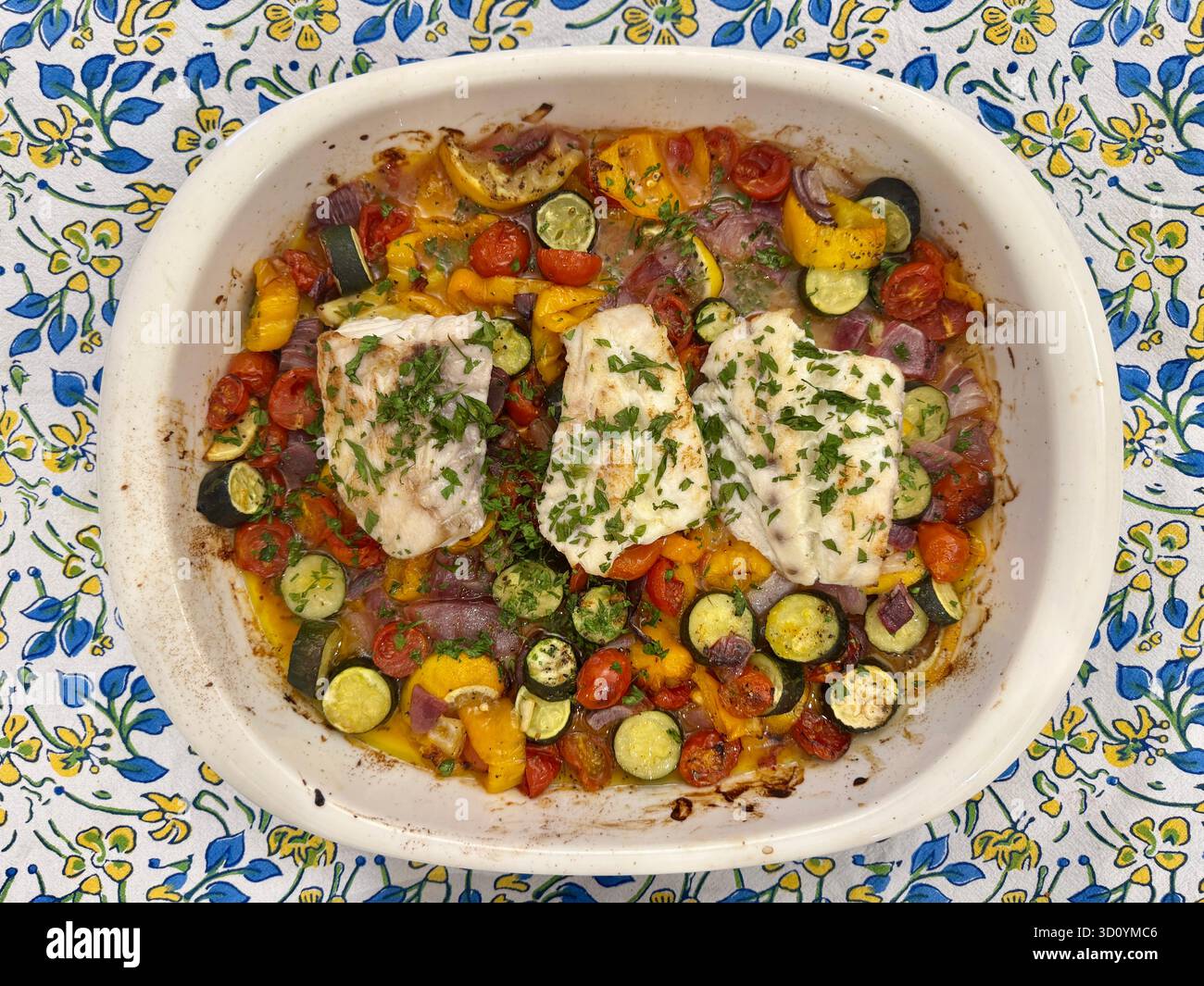 Baked tray of cod fillets over a layer of roasted vegetables Stock ...