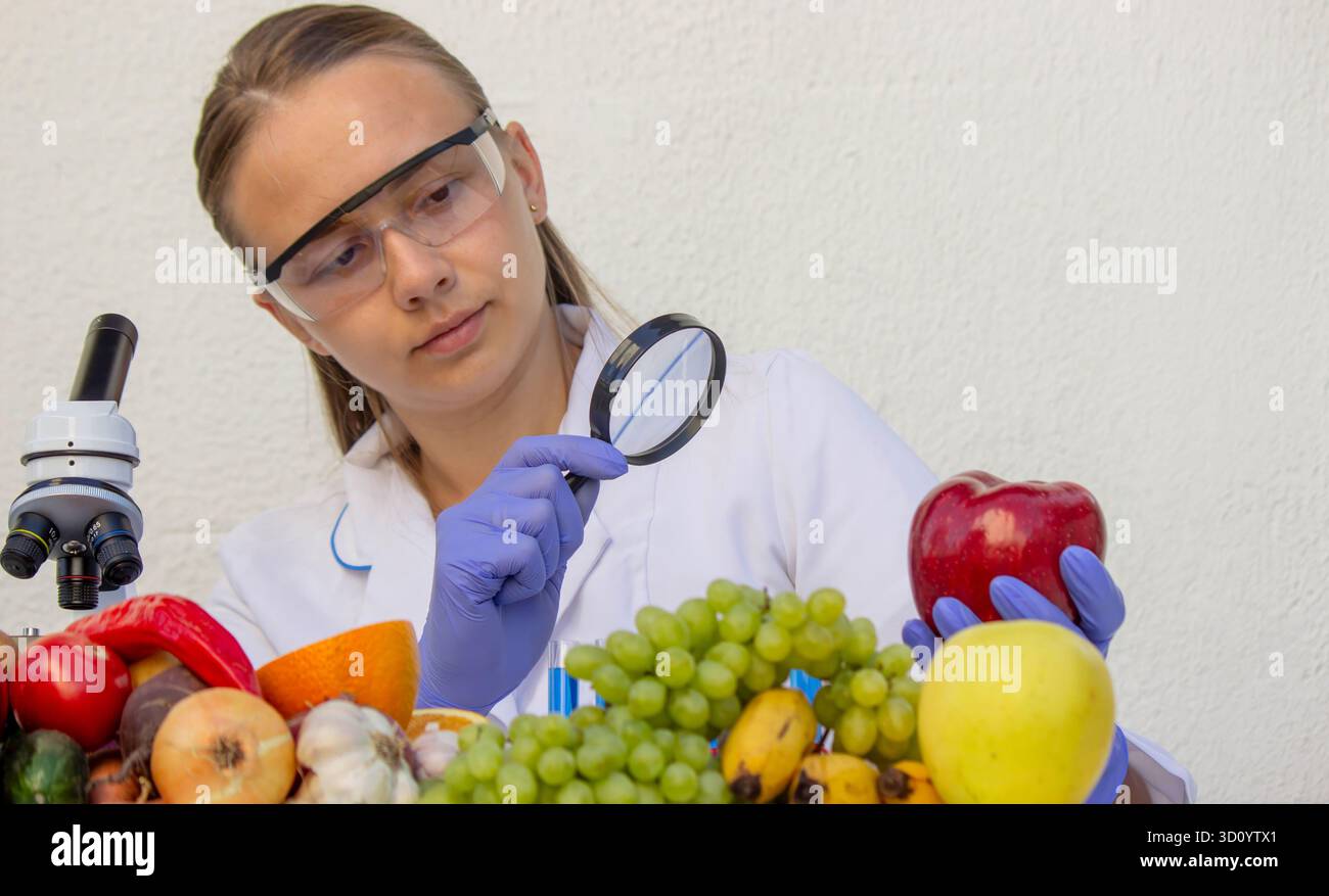 Female scientist examining fresh fruits and vegetables with a ...