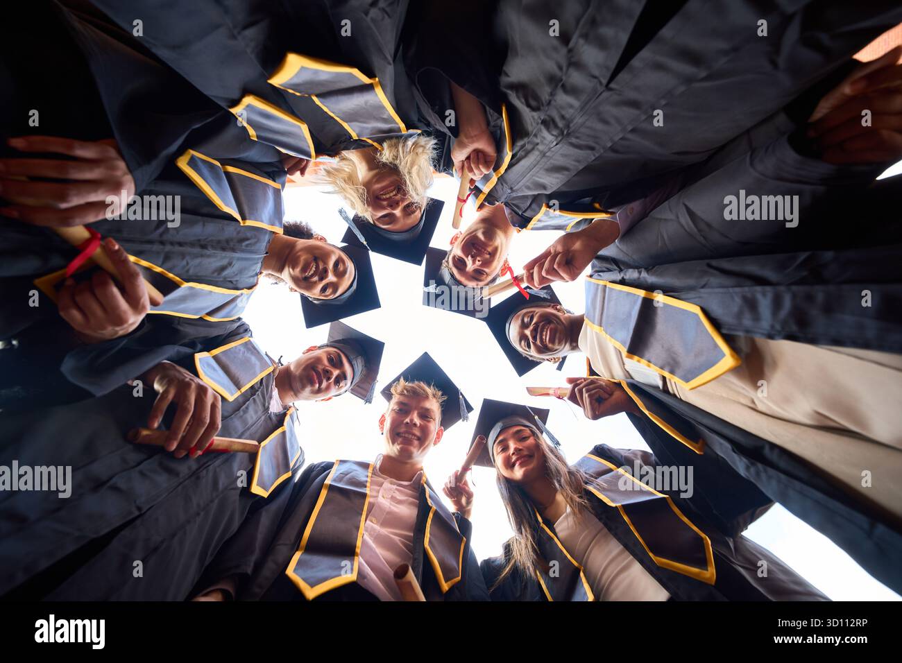 Diverse students celebrating graduation, holding diplomas in a circle ...