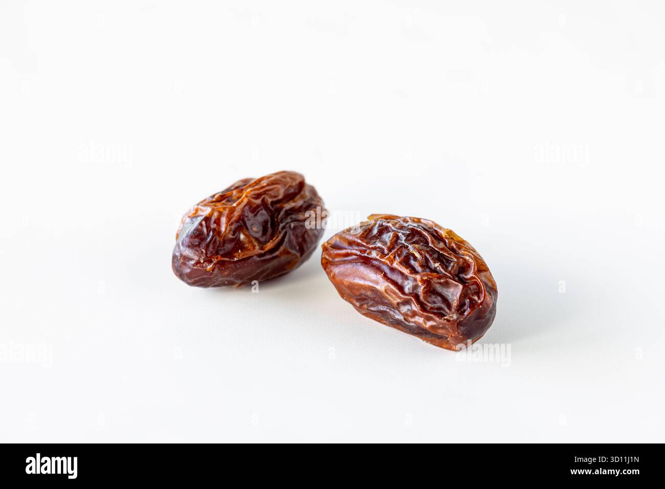 Two single whole organic medjool dates isolated against a white ...