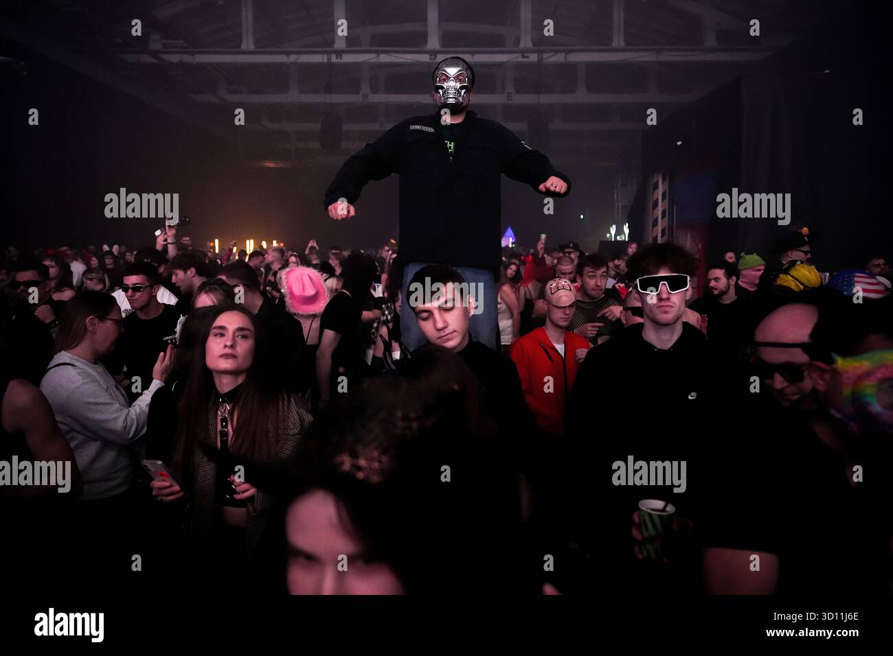 A person wearing a silver skeleton mask dances during a Halloween rave ...