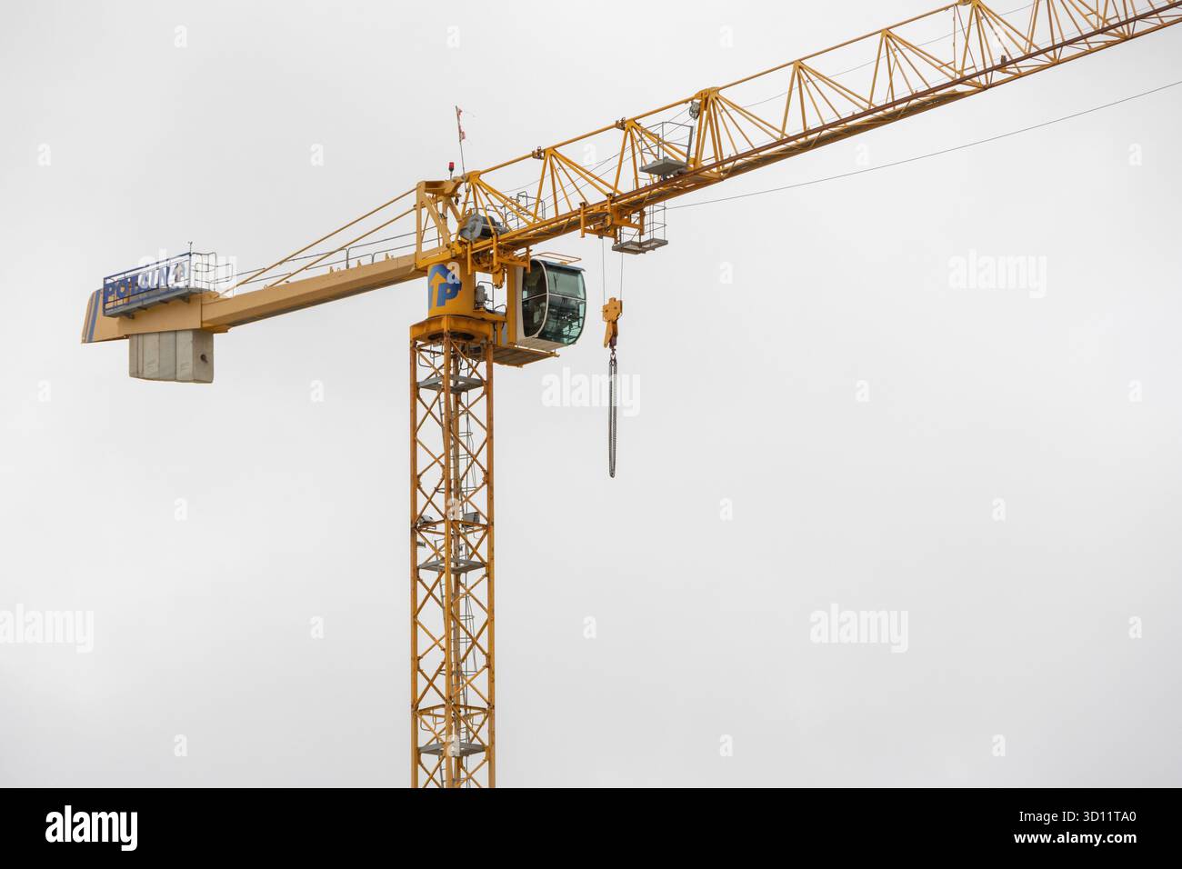 Yellow tower crane operating on a construction site, lifting heavy ...