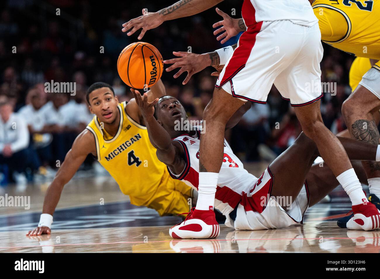 St. John guard Joson Sanon and Michigan guard Nimari Burnett (4) fall ...