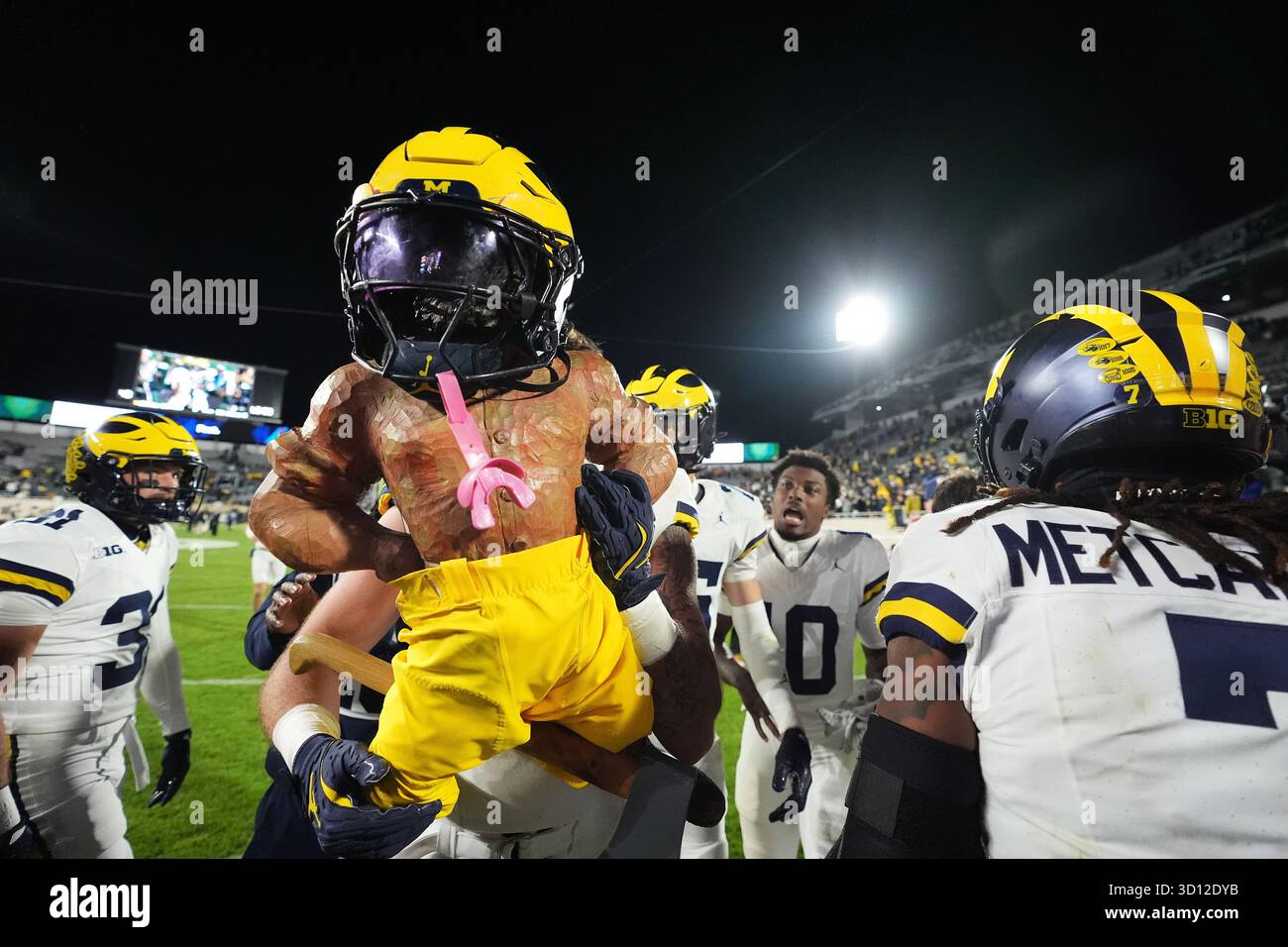 Michigan players hold up the Paul Bunyan Trophy after the team's win ...