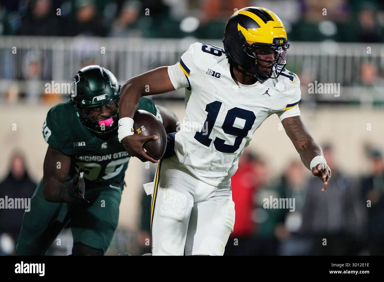 Michigan quarterback Bryce Underwood, right, runs from Michigan State ...