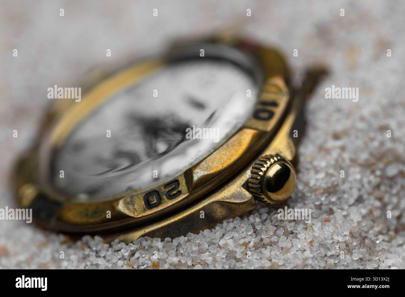 A close-up of the winding crown of an old brass watch case half-buried ...