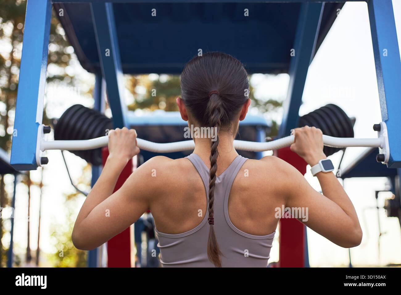 Young adult Caucasian woman exercising outdoors using pull up bar ...