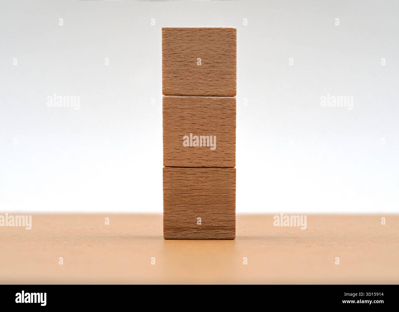A set of three wooden blocks is placed vertically on a smooth surface ...