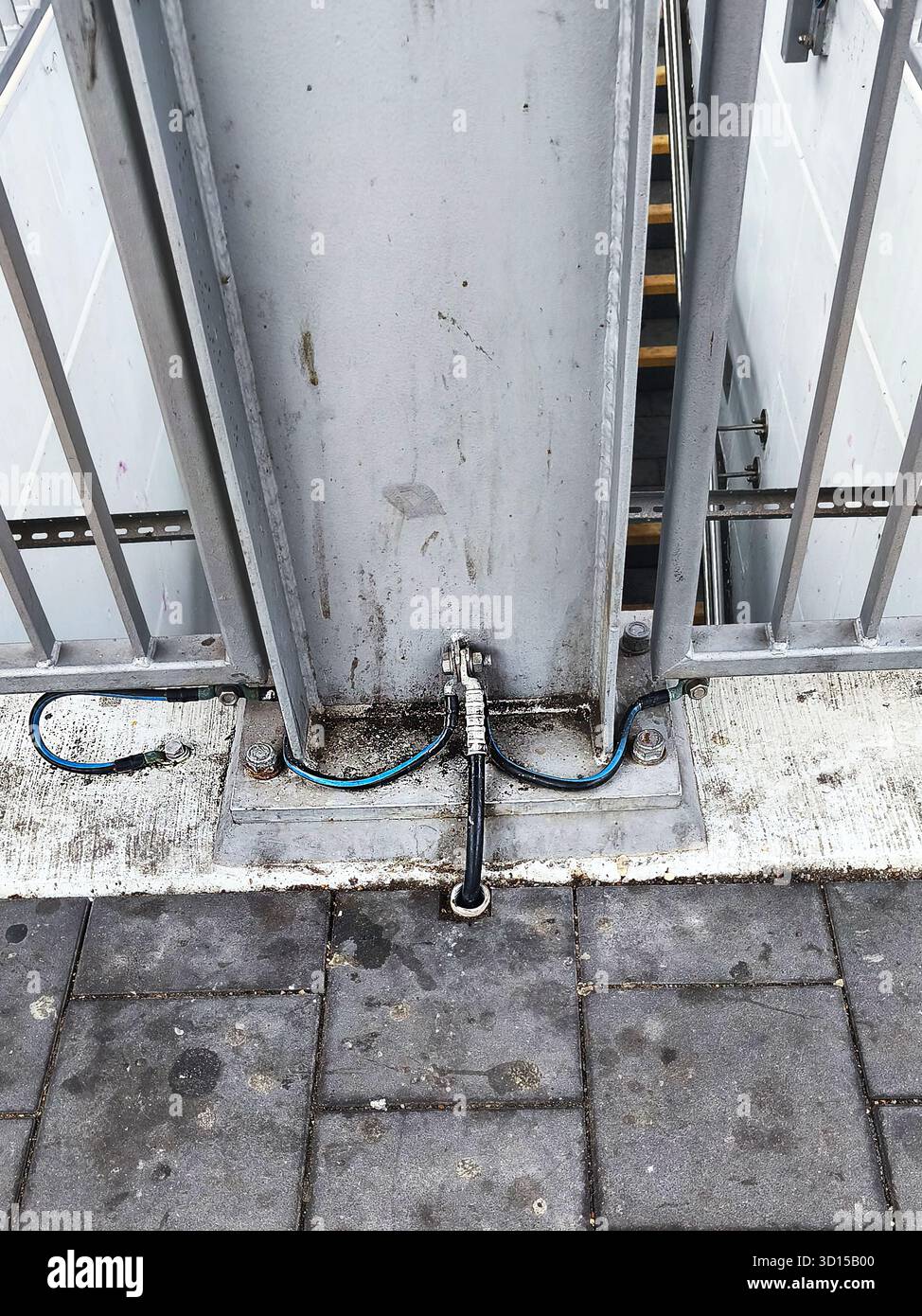 Close-up of metal structures on a train station platform connected to grounding wires, showing ...