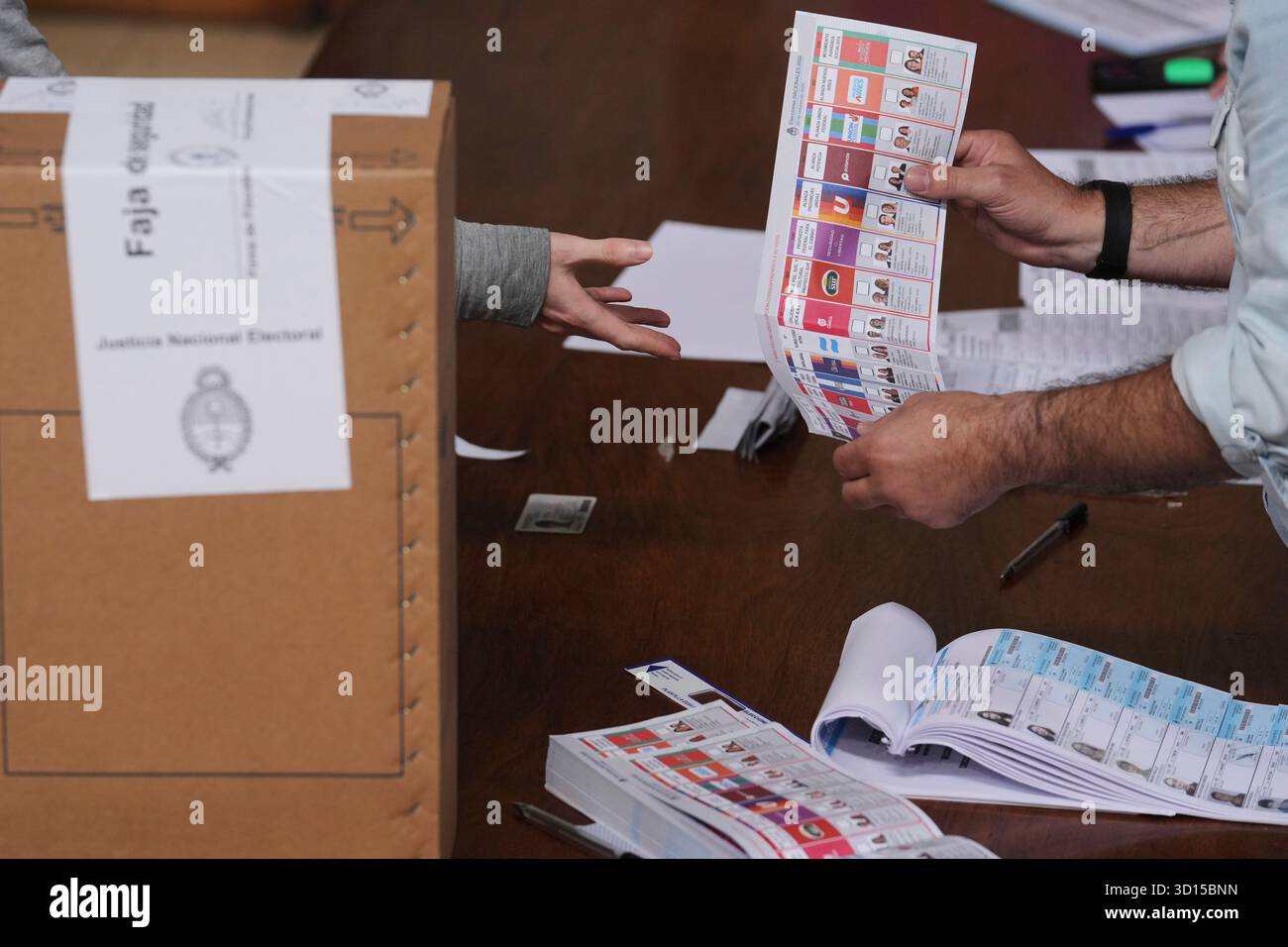 An electoral official handles a ballot to a voter during legislative ...