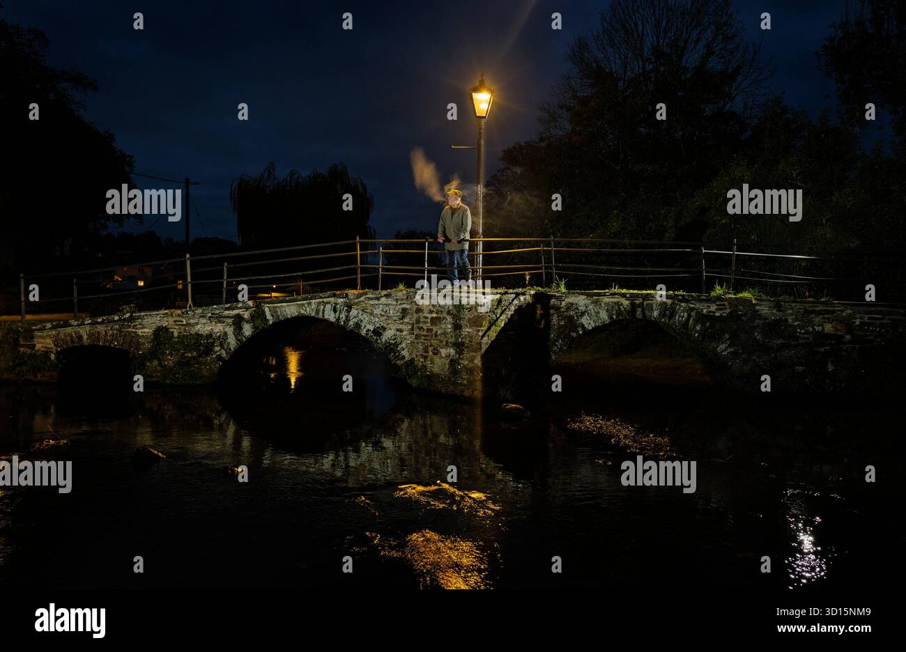 an old man having a smoke on a bridge at night under a lamp post Stock ...