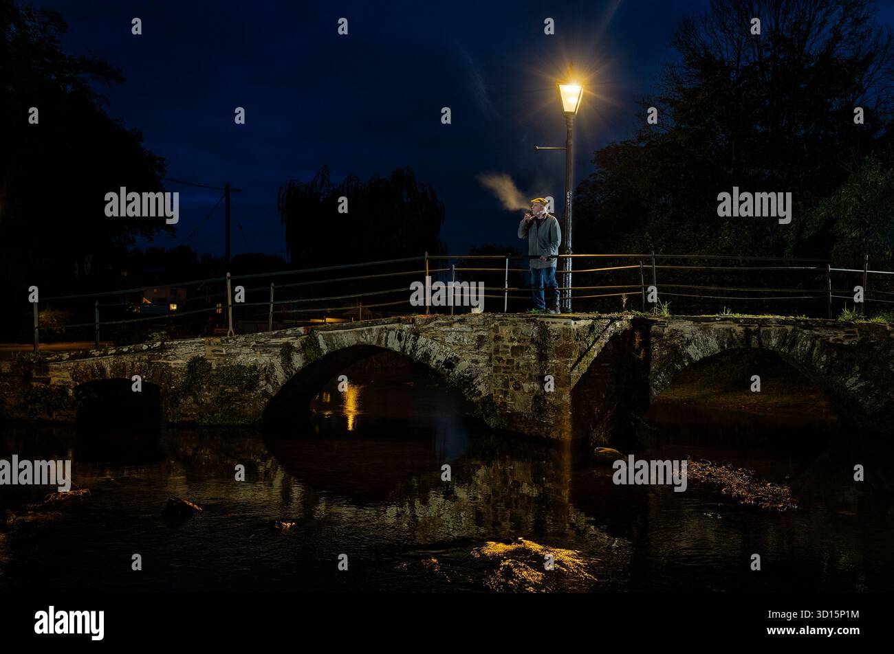 an old man having a smoke on a bridge at night under a lamp post Stock ...