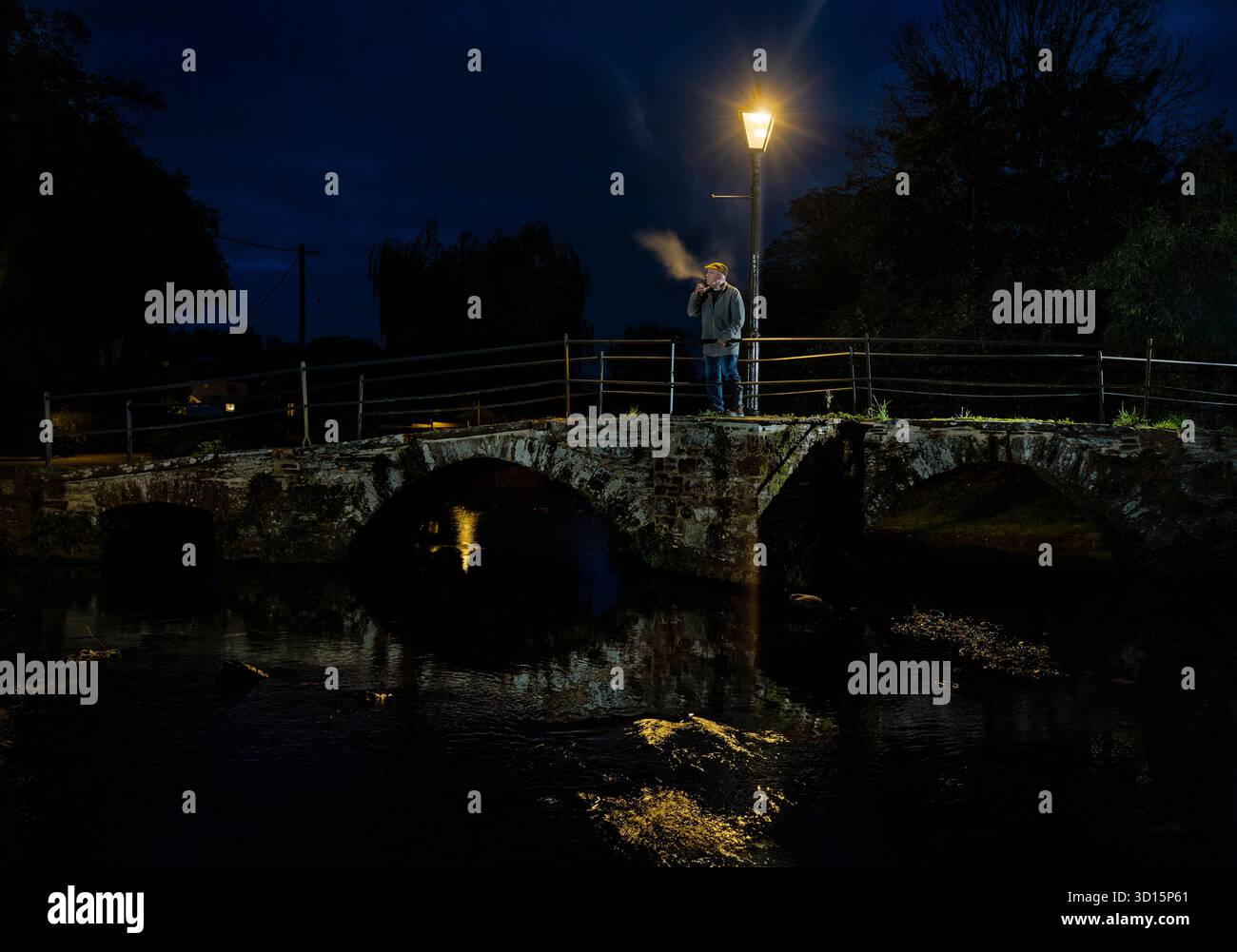 an old man having a smoke on a bridge at night under a lamp post Stock ...