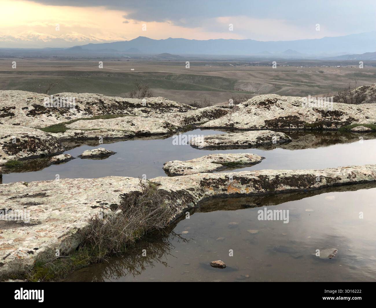 Chain of shallow pools on sculpted bedrock with distant mountain ranges ...