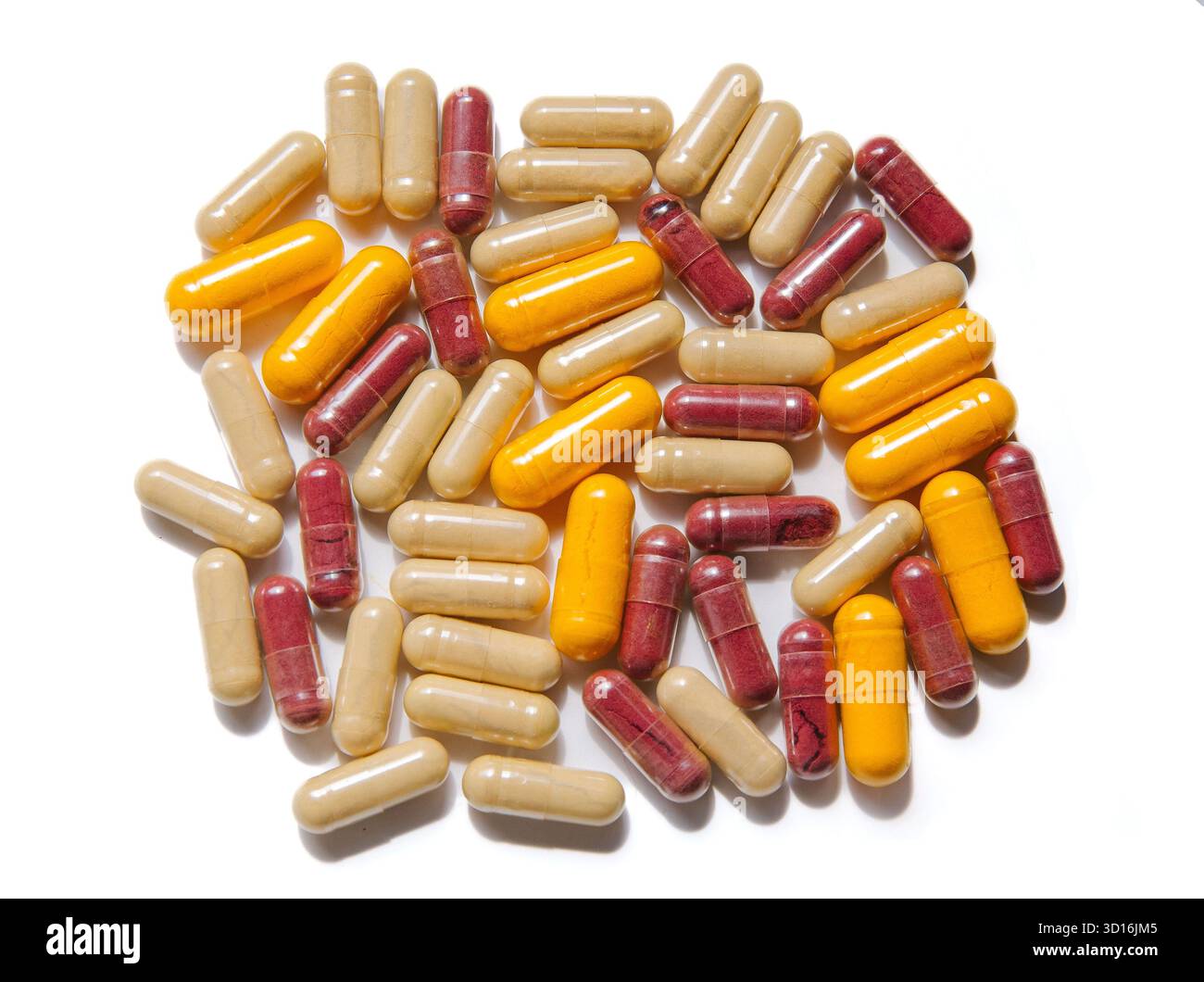 Assorted capsule medication in yellow, red, and tan colors on white ...