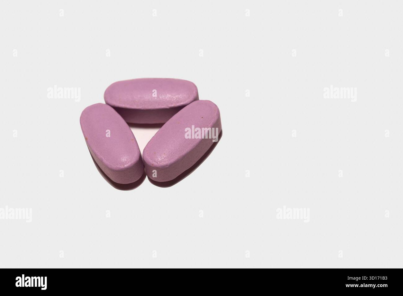 Medicines, three elongated pink pills on a white background, arranged ...