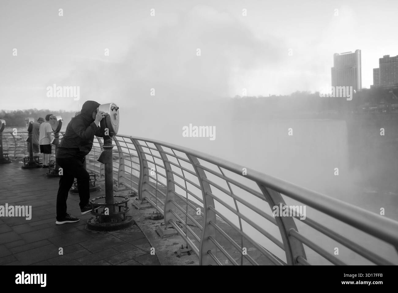 Black and white photo of a visitor looking through a binocular viewer ...