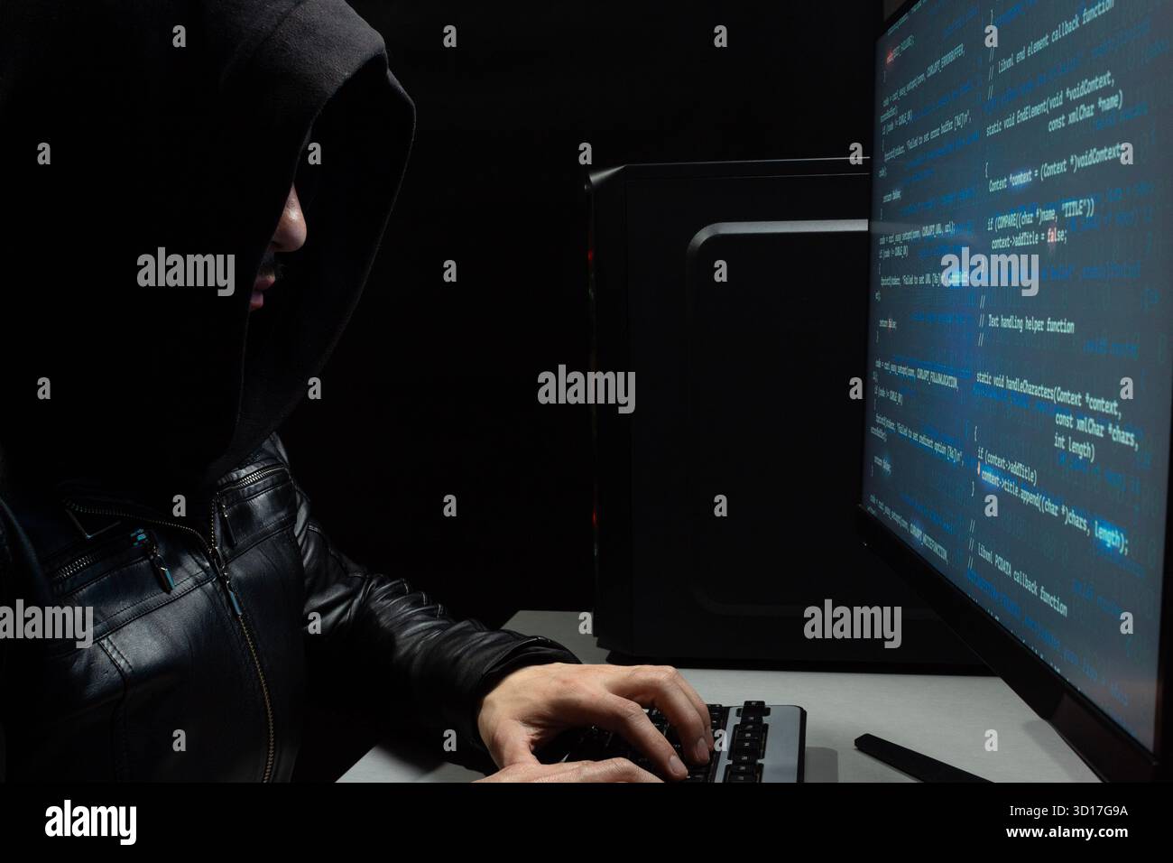 close up to a hooded man writing on a keyboard computer in front of ...