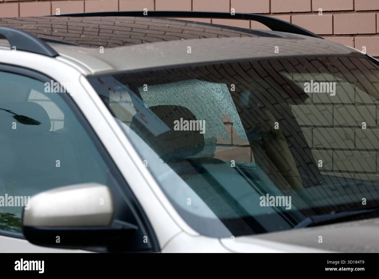 A shattered side window of a vehicle is seen as police work at the ...