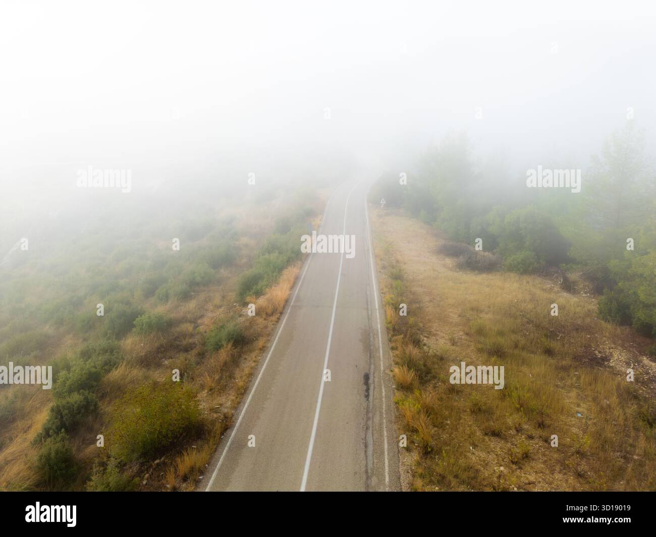 Aerial view of an empty mountain road disappearing into fog Stock Photo ...