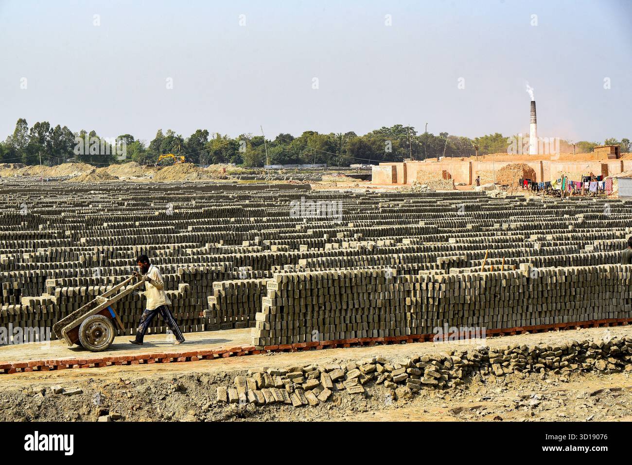 Industrial Brick Yard With Stacks Of Bricks And A Worker Pushing A ...