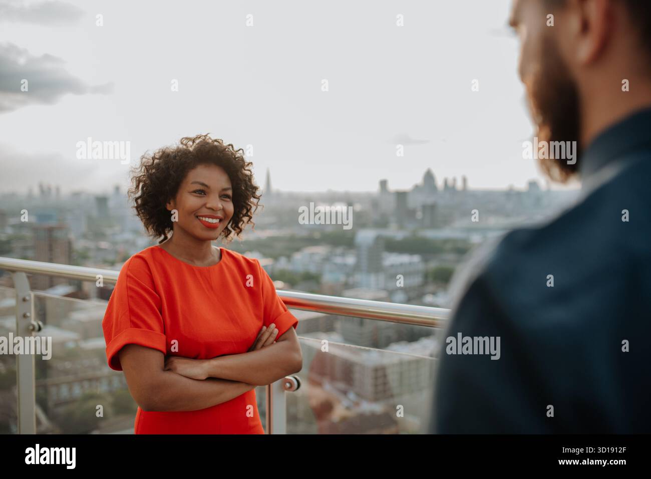 Real estate agent talking to client on the rooftop of a modern building ...