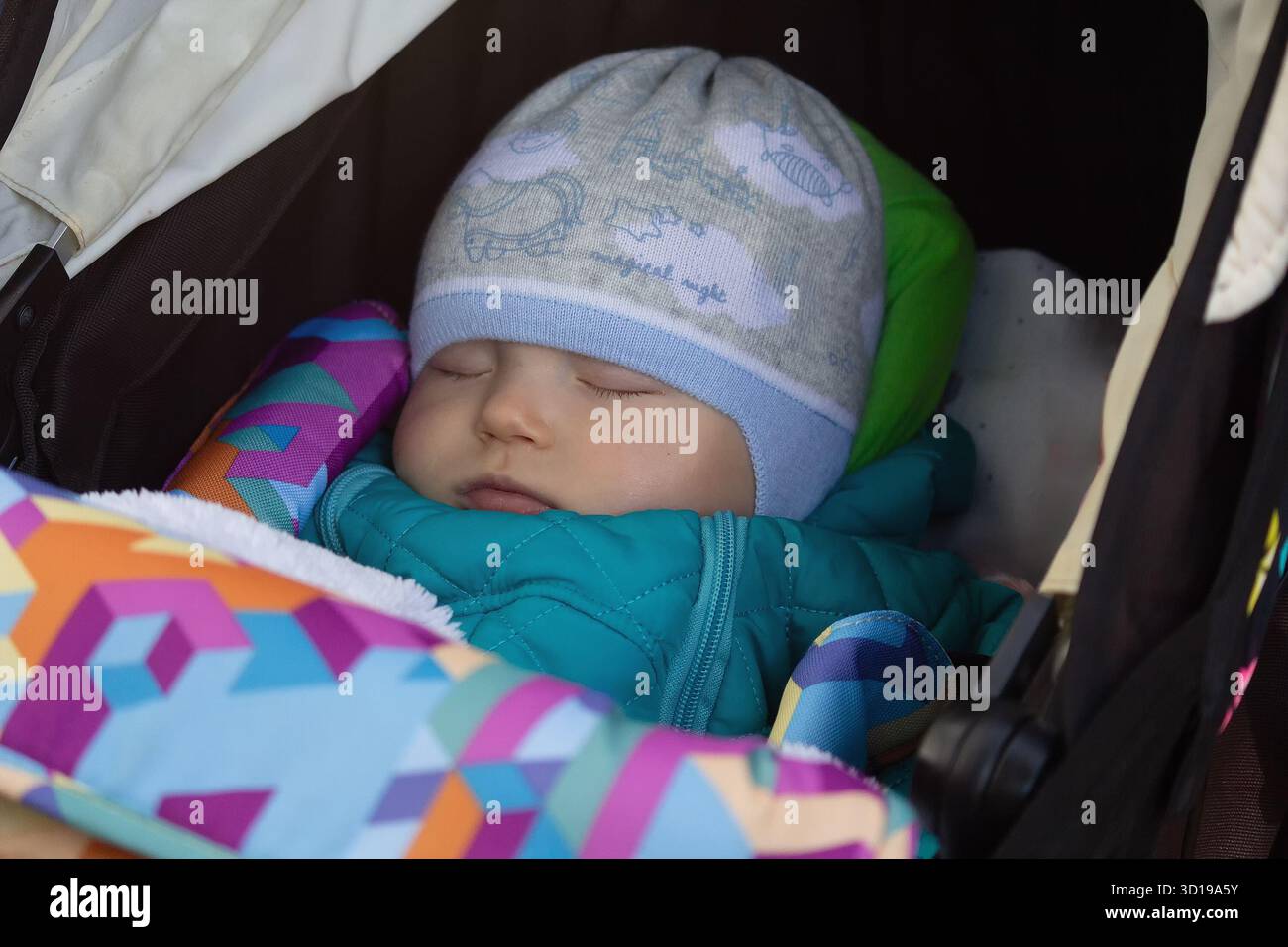 Baby in jacket and hat sleeping in stroller on a walk in a park. Child ...