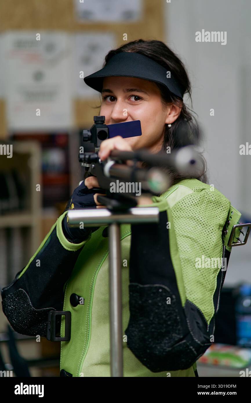 Focused young woman aiming with air rifle, precision shooting sport ...