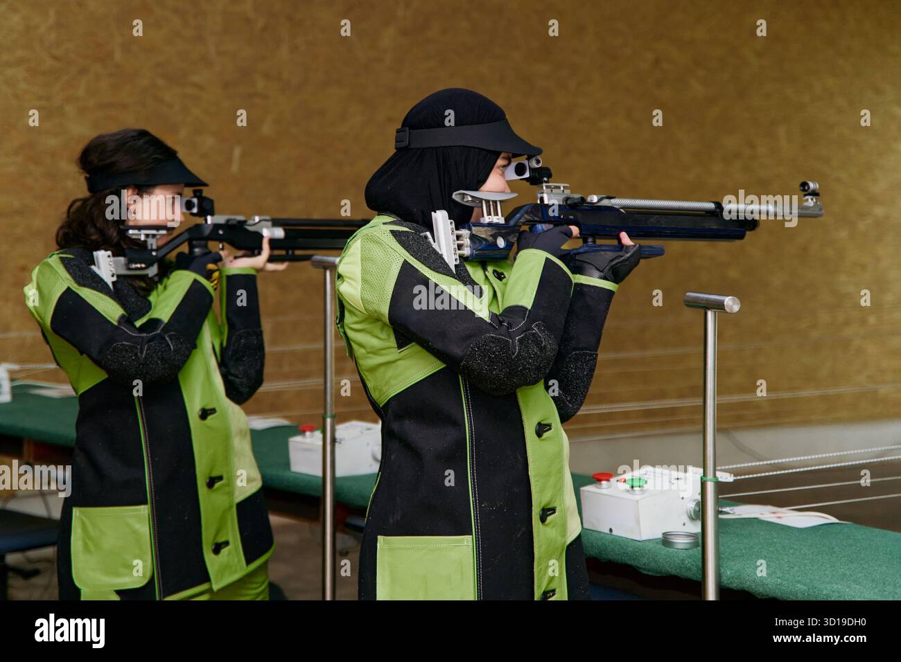 Two female athletes aiming air rifles in shooting competition ...