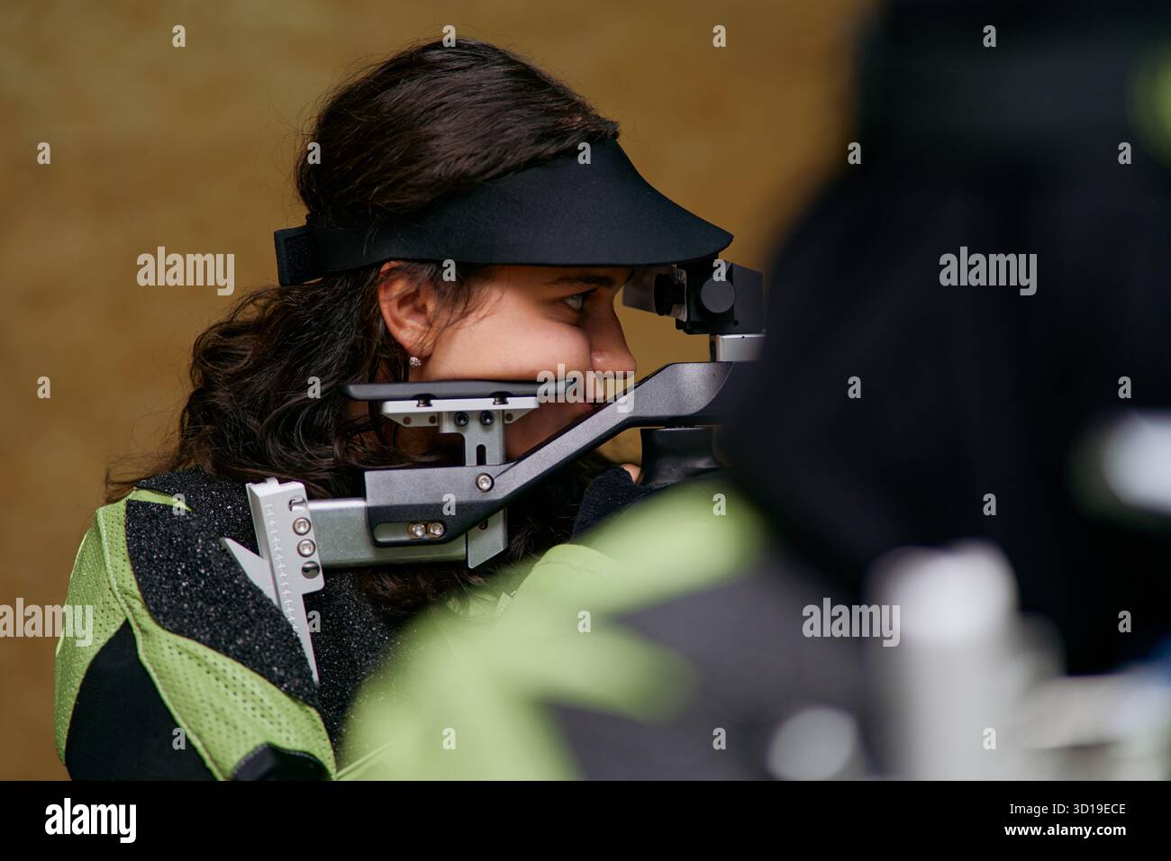 Focused young woman aiming rifle in shooting competition, demonstrating ...
