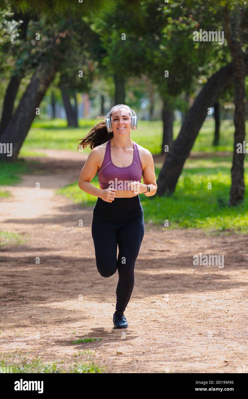 Vertical photo of woman jogging outdoors in park wearing sportswear and ...