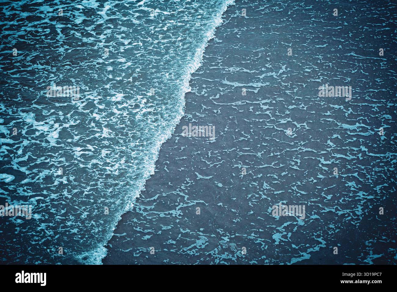 Foamy, shallow, tidal waves reaching the sandy shore. Top down view ...