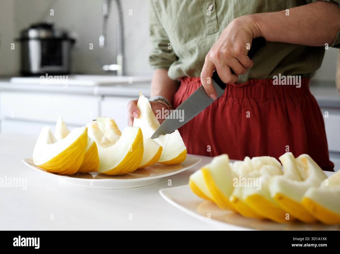 Woman Cutting Melon Into Pieces In The Kitchen Close-Up Stock Photo - Alamy