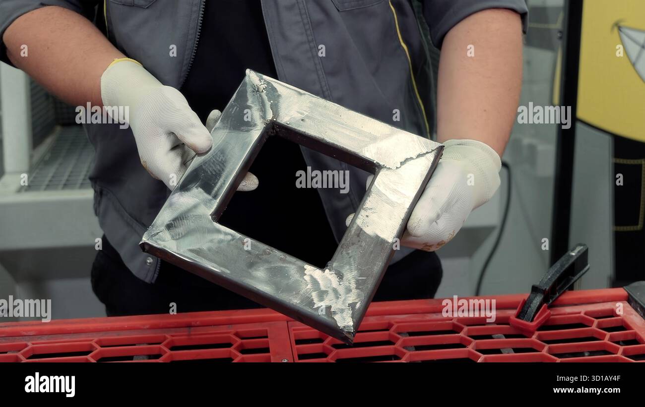 Metalworker holding welded steel frame piece. A worker wearing gloves ...