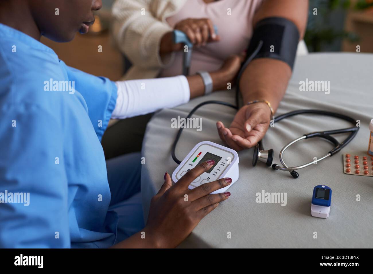 Black female nurse measuring blood pressure of geriatric female patient ...