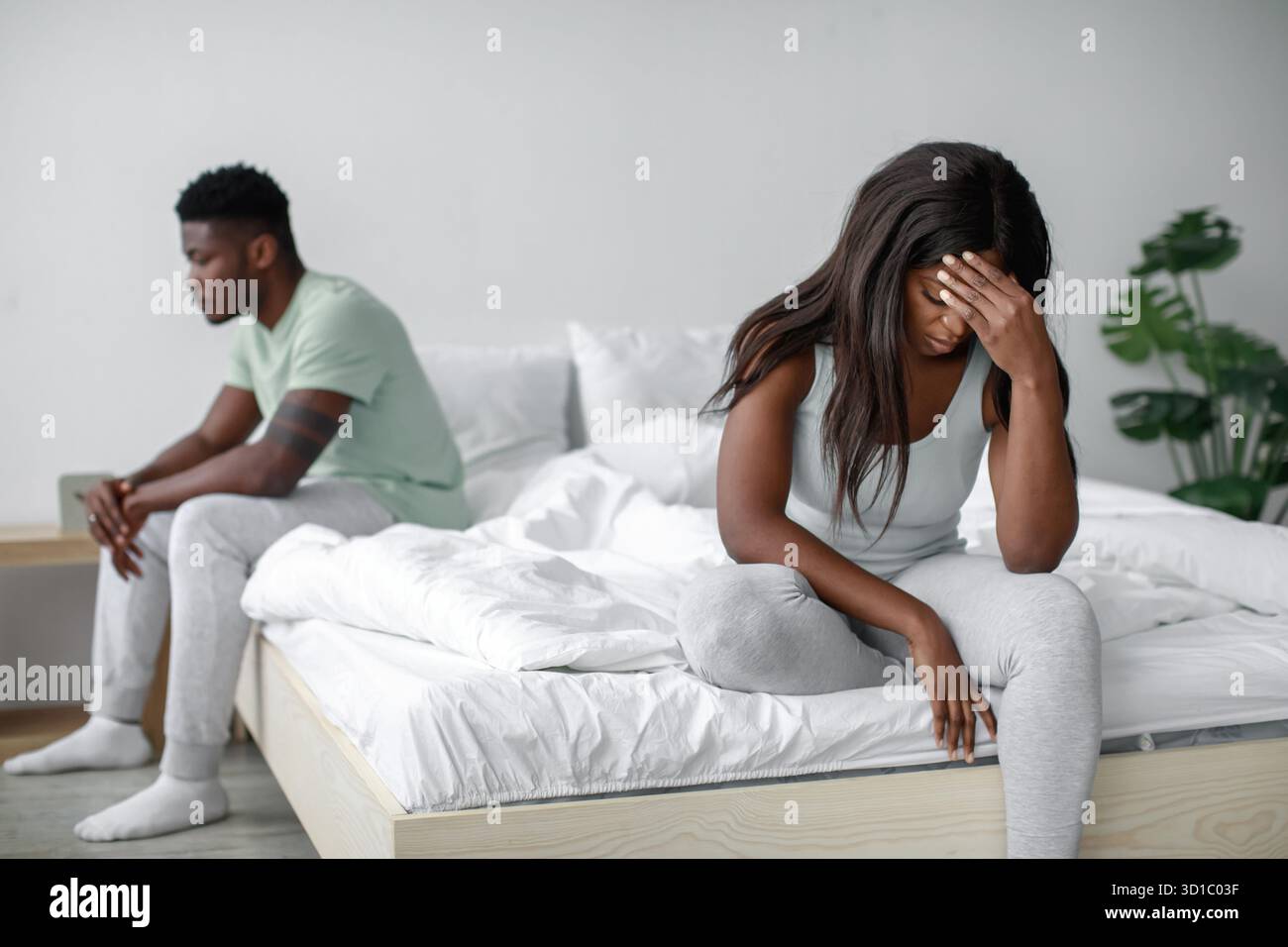 Two People in a Tense Moment, Sitting on a Bed in a Softly Lit Room ...