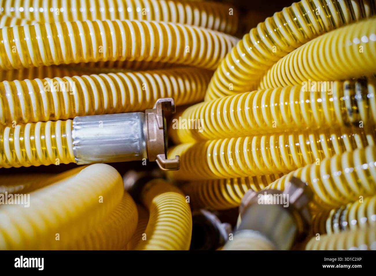 Close-up of yellow corrugated industrial hoses with metallic fittings ...
