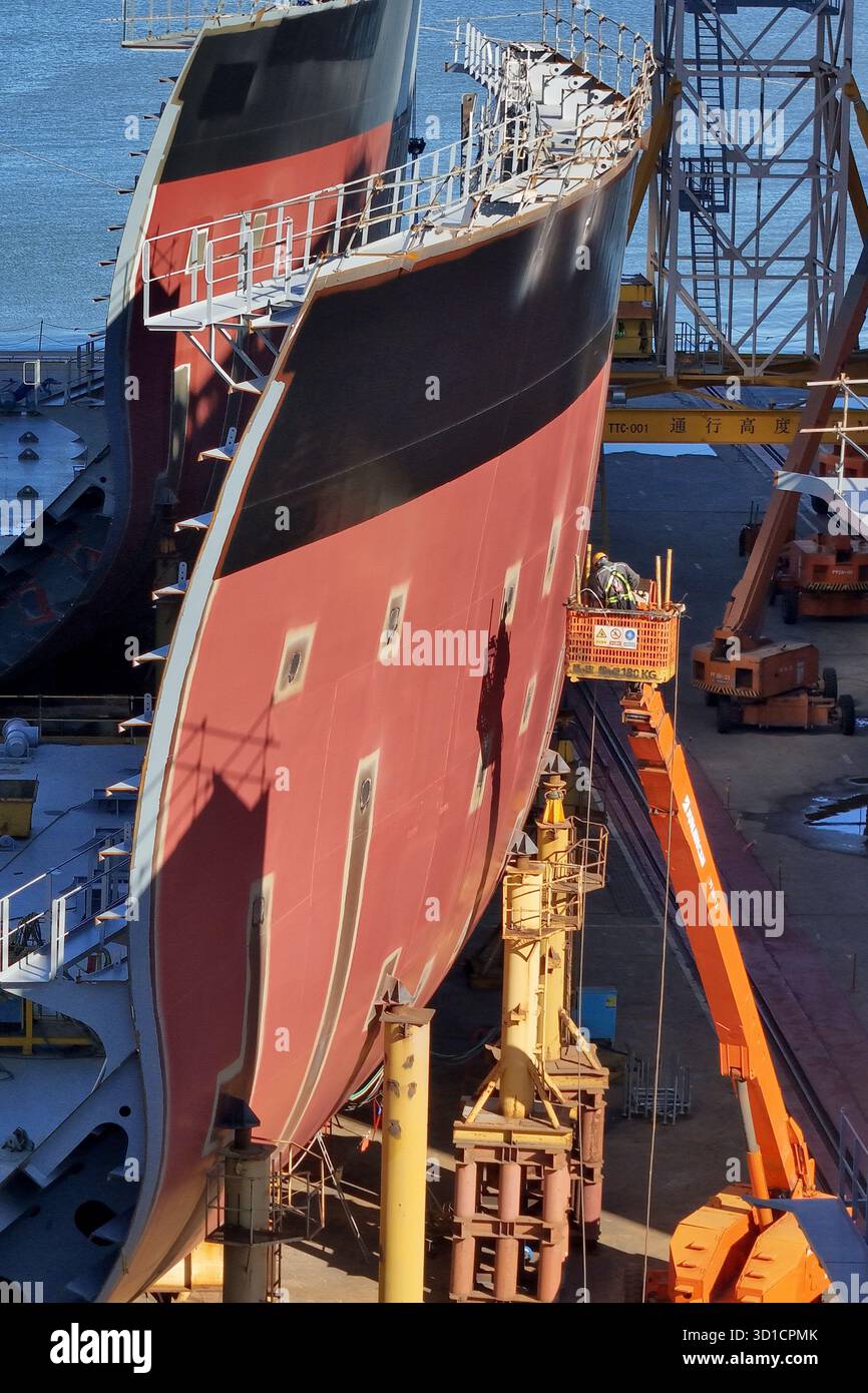 Workers build large ship hull sections on an aerial work platform at a ...