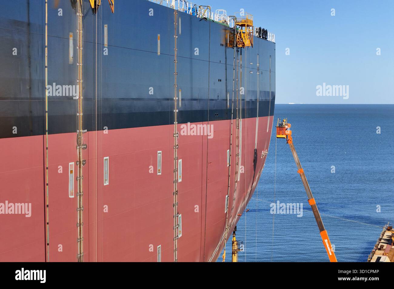 Workers build large ship hull sections on an aerial work platform at a ...