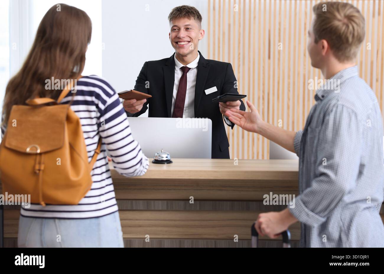 Receptionist giving passports to guests at reception desk indoors Stock ...