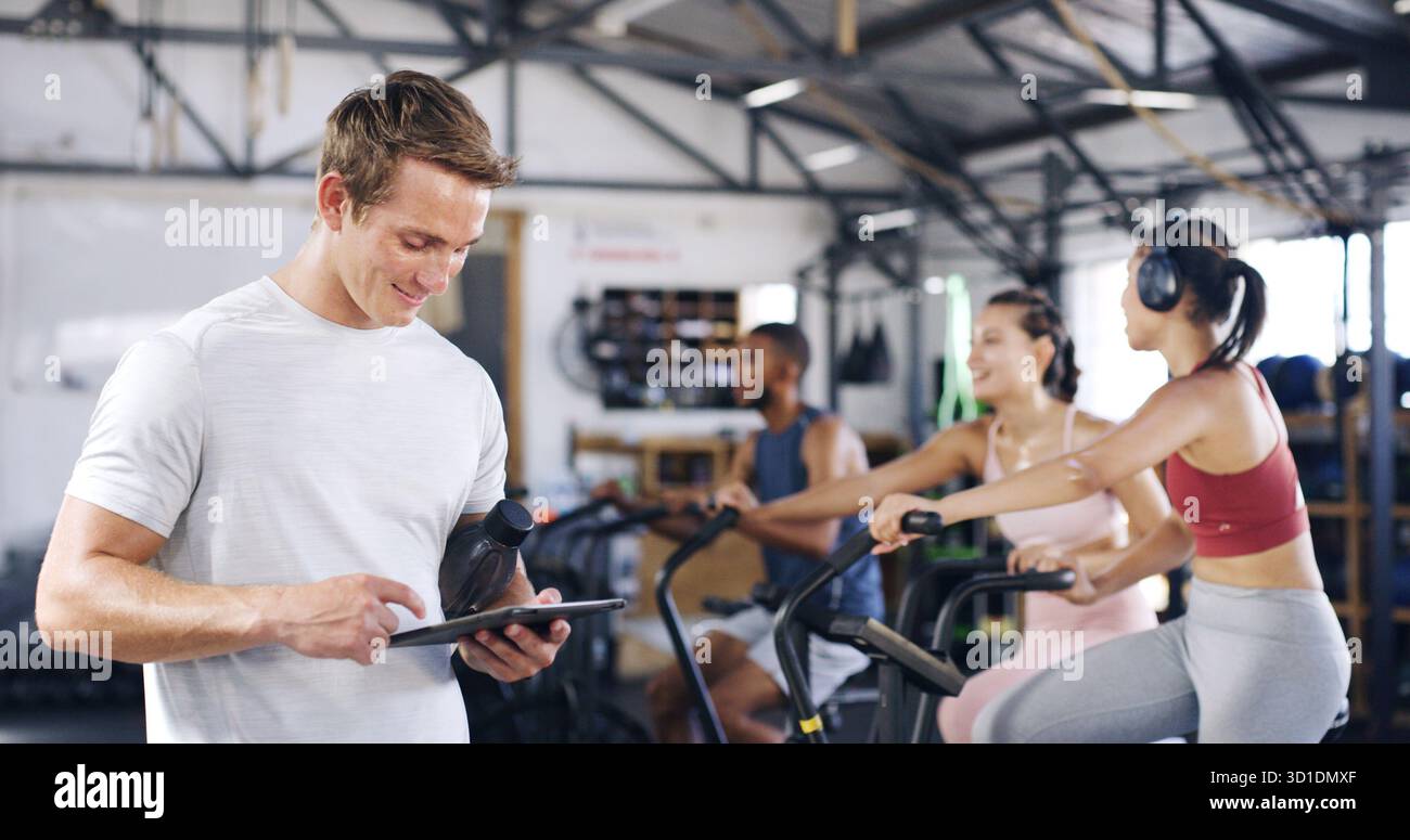 Man, personal trainer and tablet with people in spin class for fitness ...