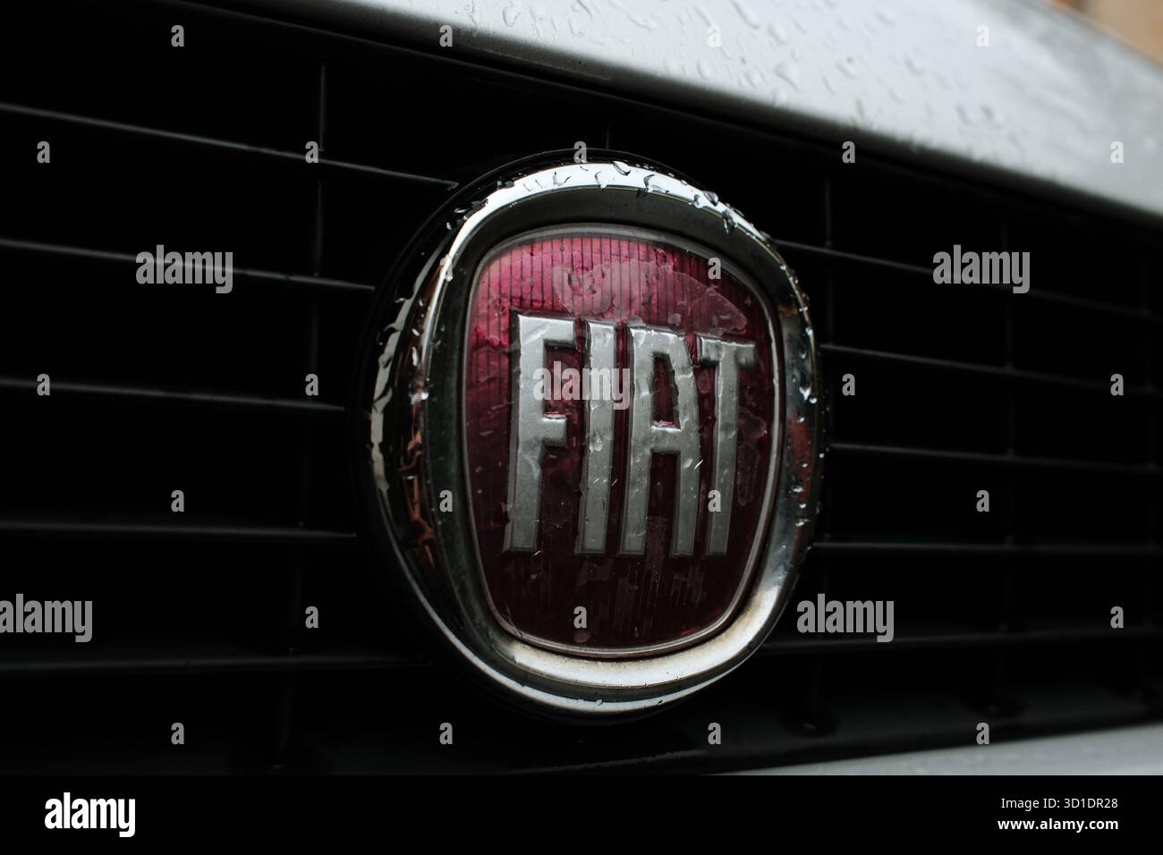 Fiat emblem on red background of car grill with raindrops and metallic ...