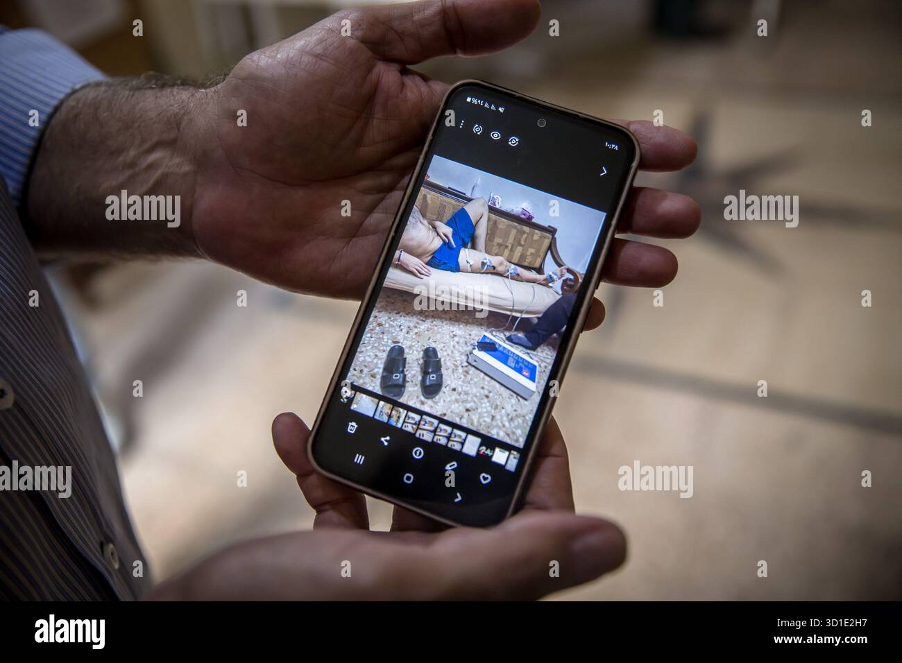 Samir Mansour holds up a photo of the injuries his son sustained during ...