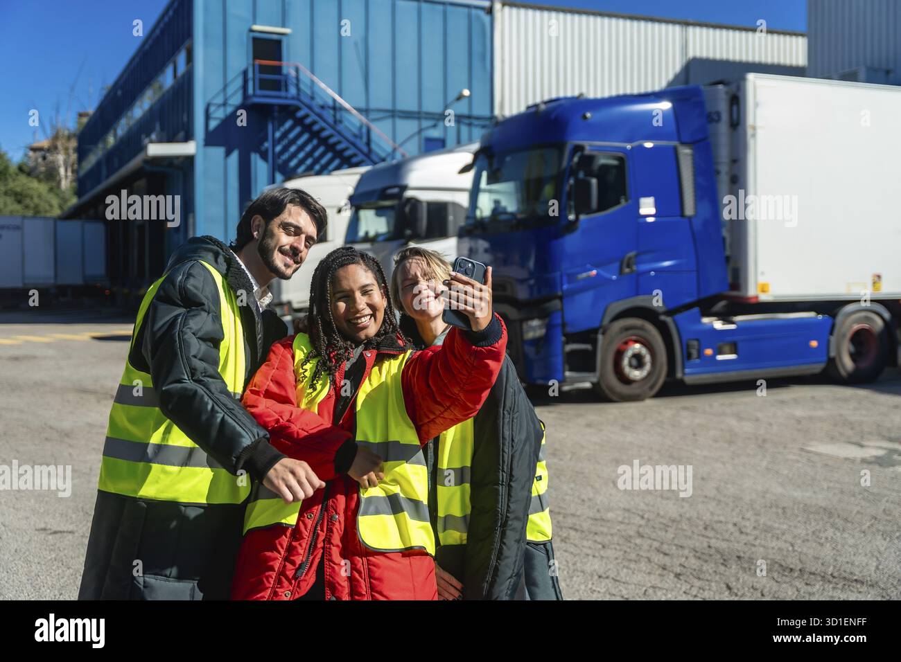 Diverse logistics team members smiling and taking a selfie outside a ...