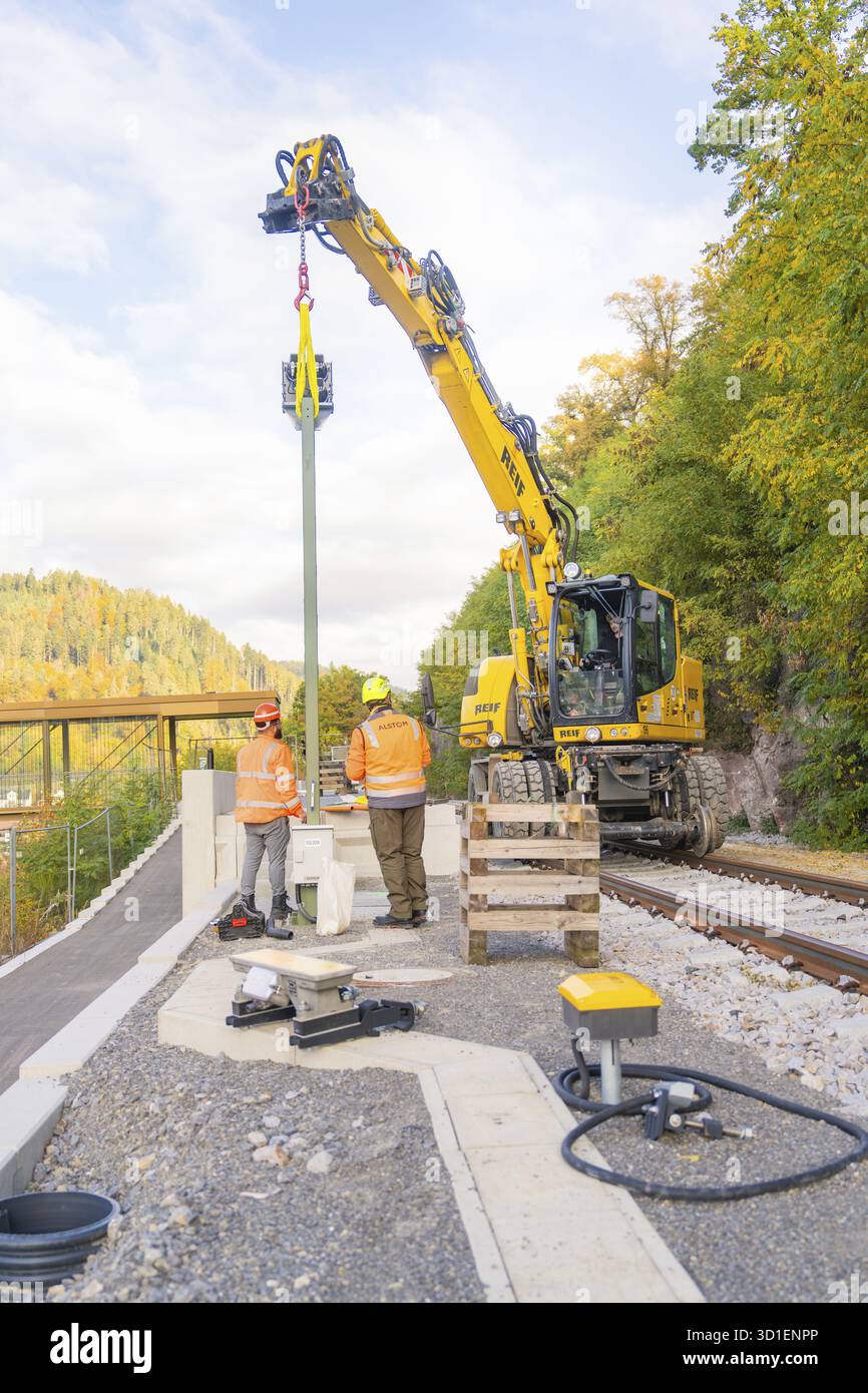 Excavator lifts object on railroad tracks, workers in protective ...