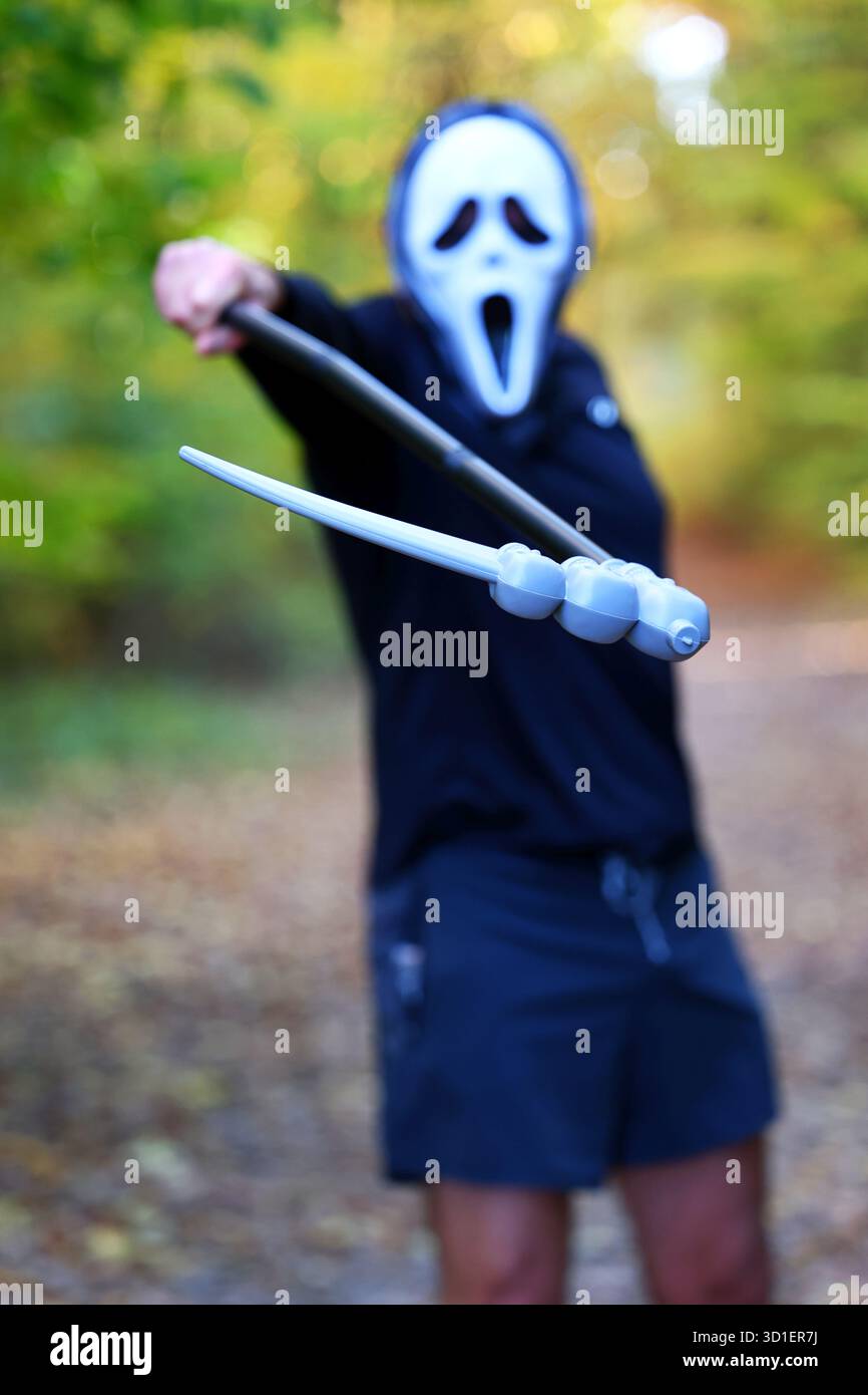 Ghostface Character Posing with Scythe in Autumn Forest Stock Photo - Alamy