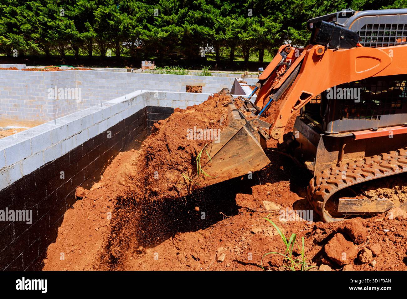 Excavator pouring dirt from ground as construction progresses on ...
